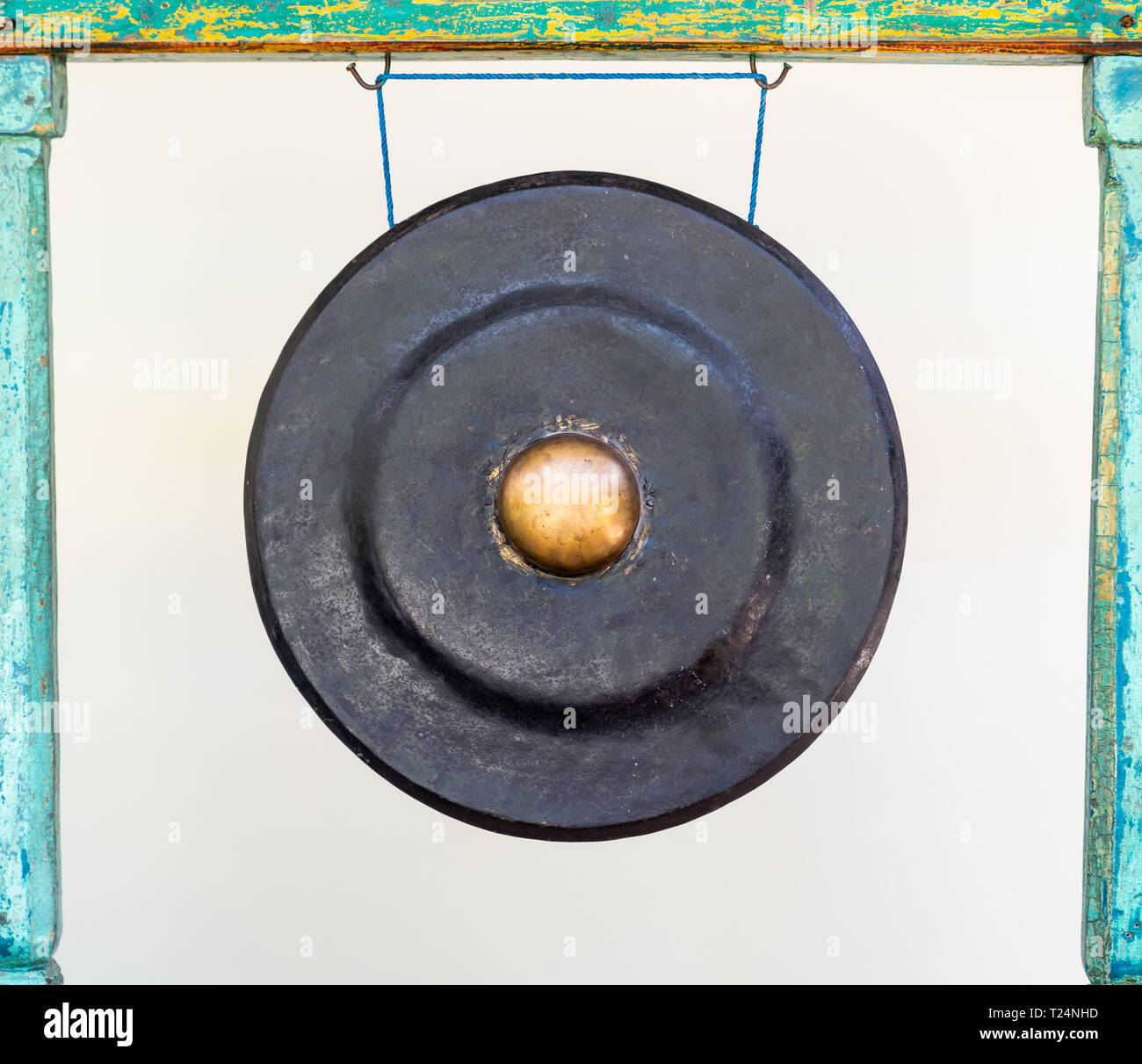 Black and golden traditional Asian gong attached to a green wood frame ...