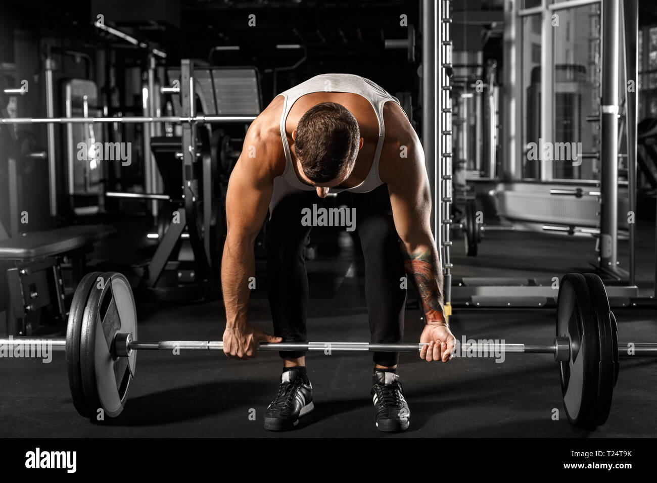 Bearded man bodybuilder at gym bending down holding barbell finishing ...