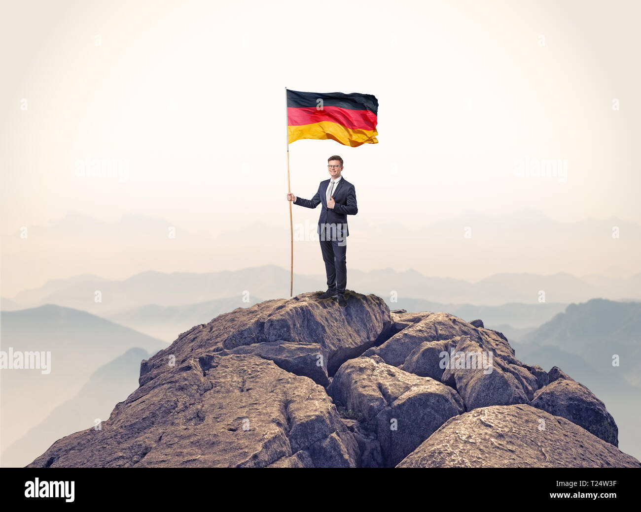 Successful businessman on the top of a mountain holding victory flag ...