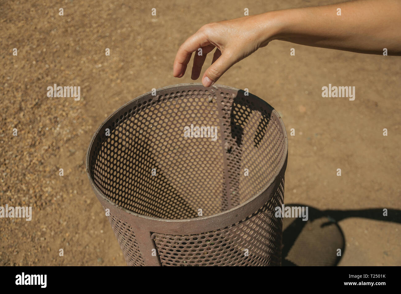 Hand of woman throwing waste inside a trash can in a park, in a sunny ...
