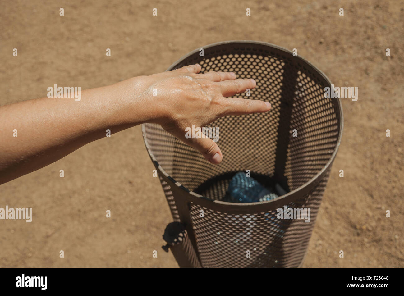 Hand of woman throwing a plastic bottle inside a trash can on a park at ...