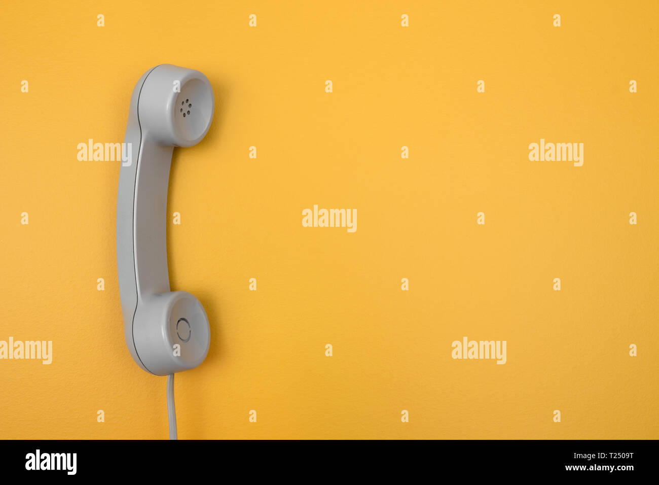 Classic gray telephone receiver on bright yellow background with copy ...