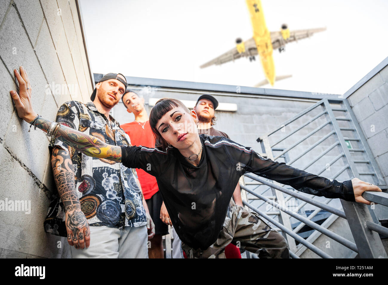 group of young rappers posing on the metal stairs of an abandoned ...