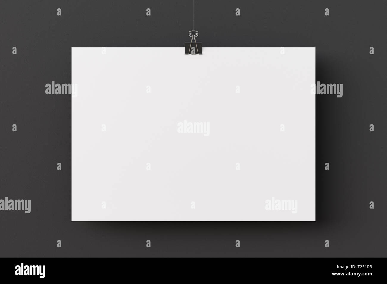 Blank horizontal paper poster hanging on binder clip on black wall ...