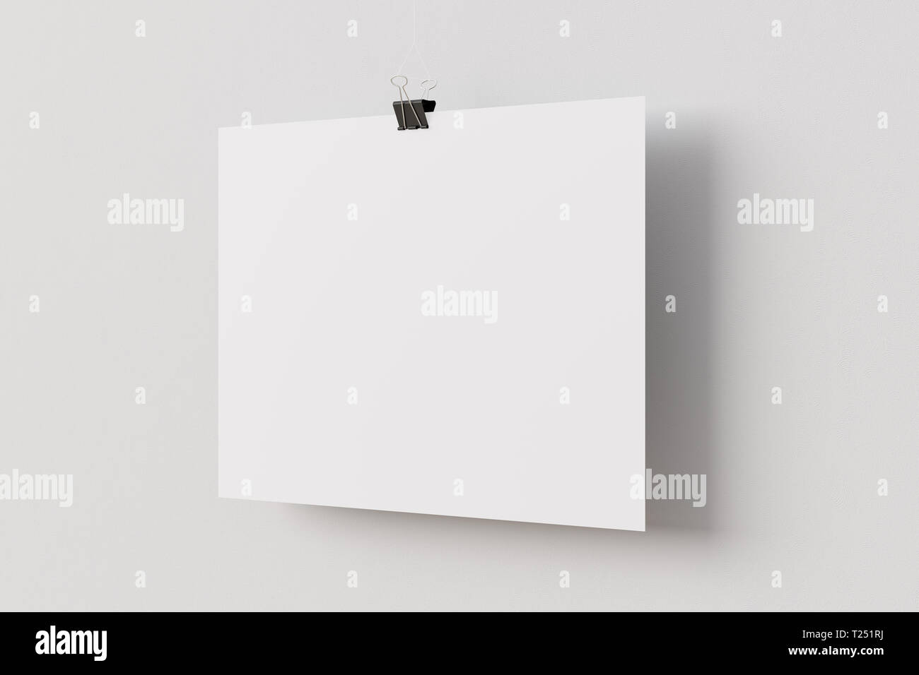 Blank horizontal paper poster hanging on binder clip on white wall ...