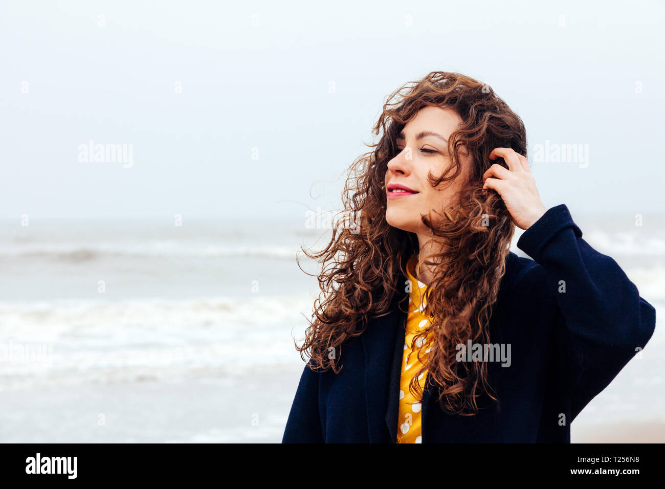 Close-up of a girl with long curly hair against a cold winter sea ...
