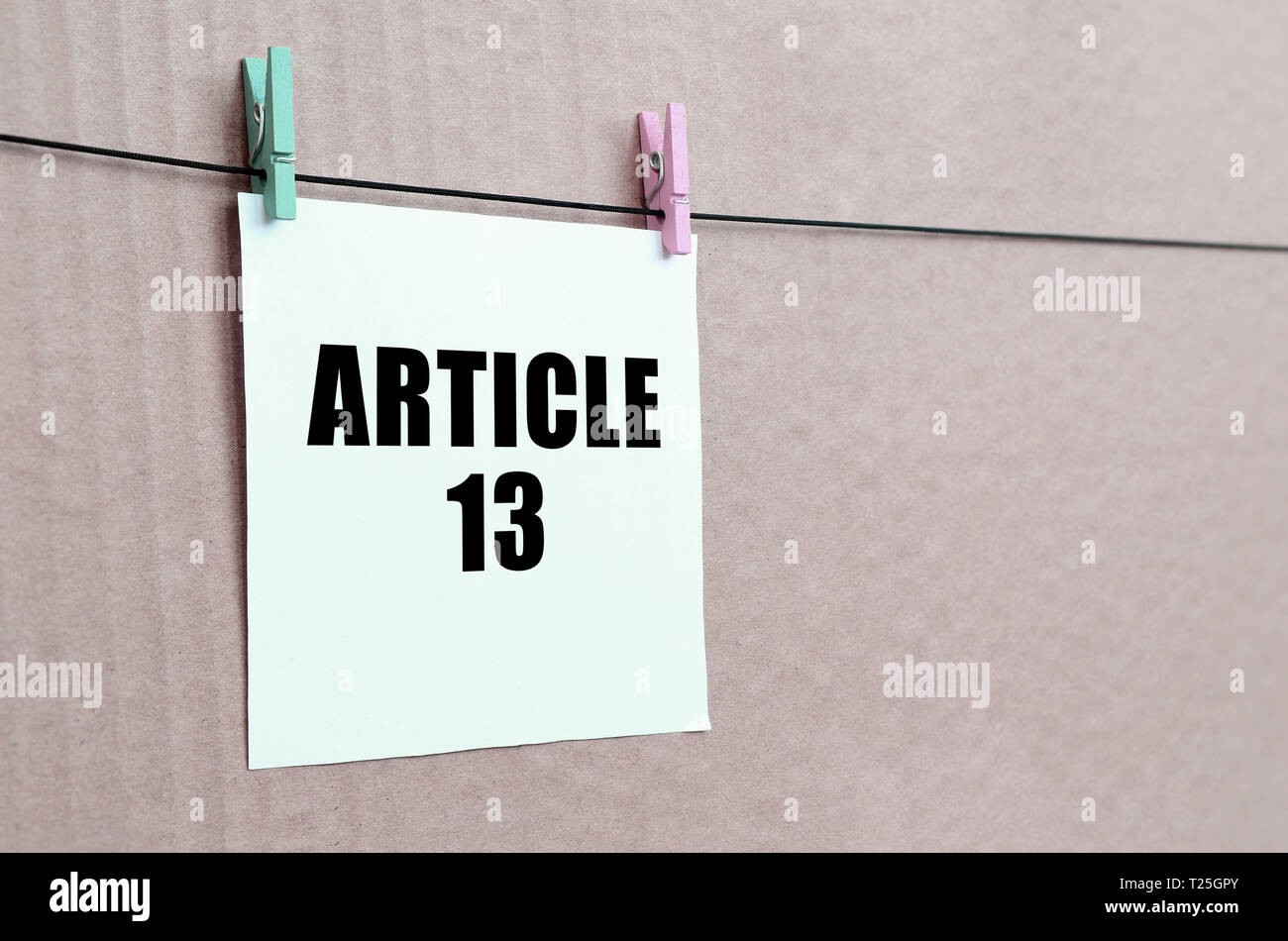 Article 13 inscription on white card on rope on a brown cardboard ...