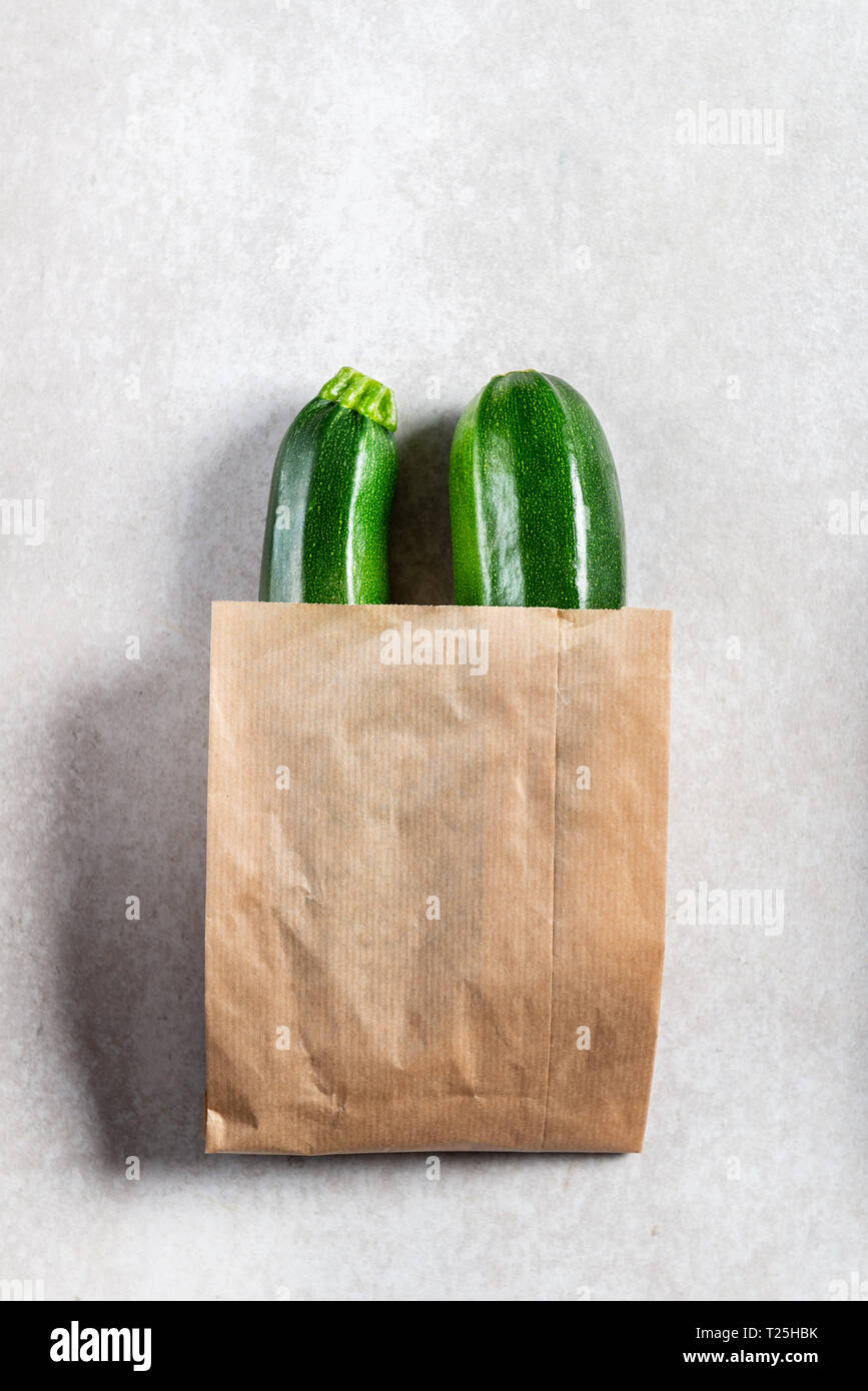 Courgettes in paper bag. Safe the planet, say no to plastic. Light grey ...