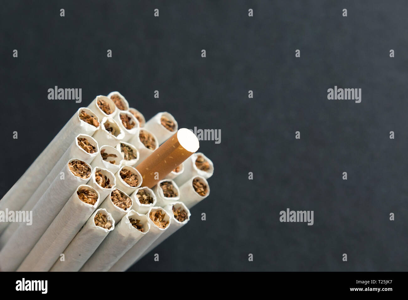 Many tobacco cigarettes on a black background. Sticks out a cigarette ...