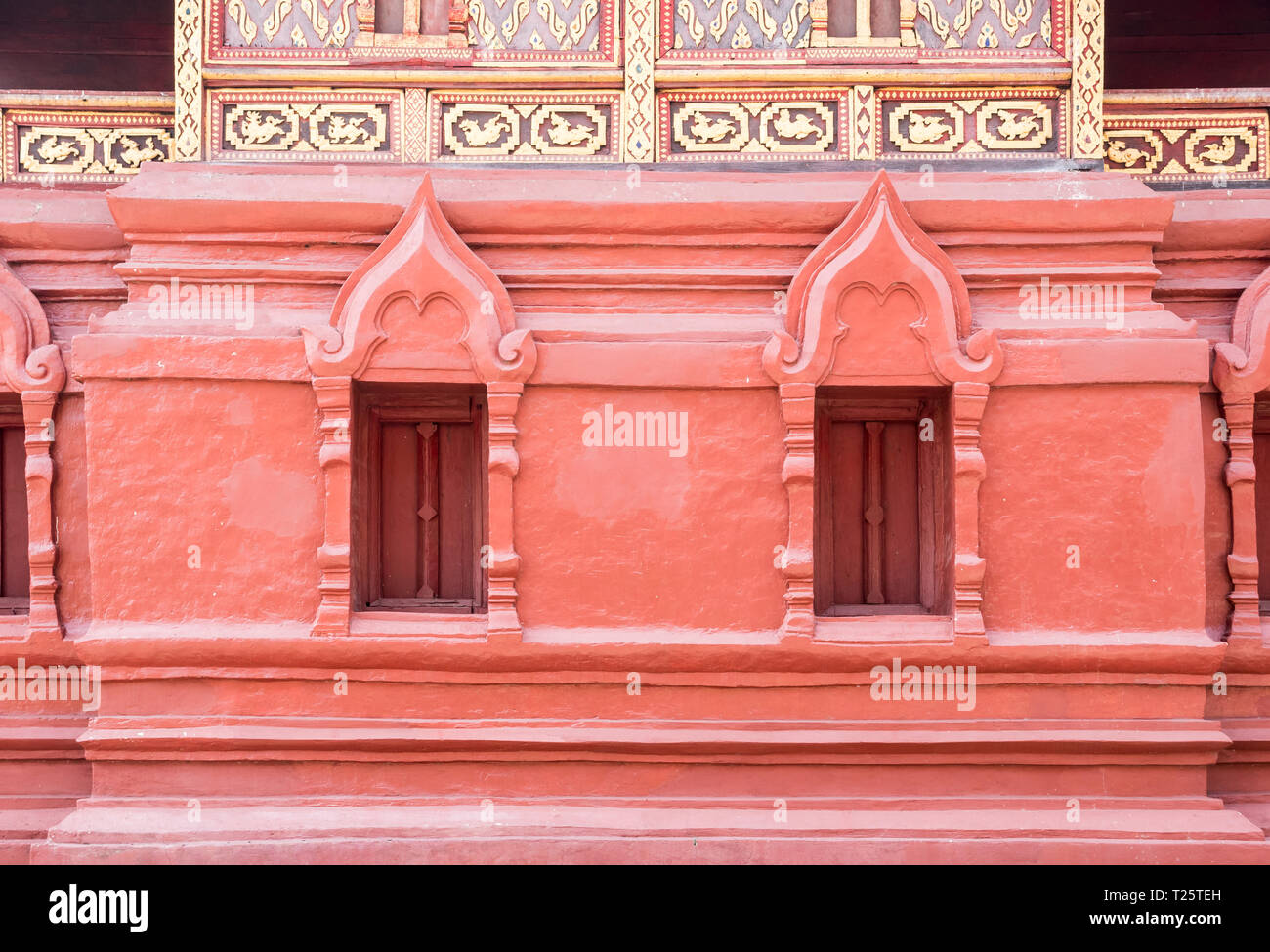 Red window frame in the traditional northern Thai style on the side of ...