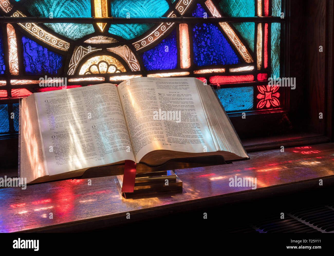Light from stained glass window falls on open bible in american church ...