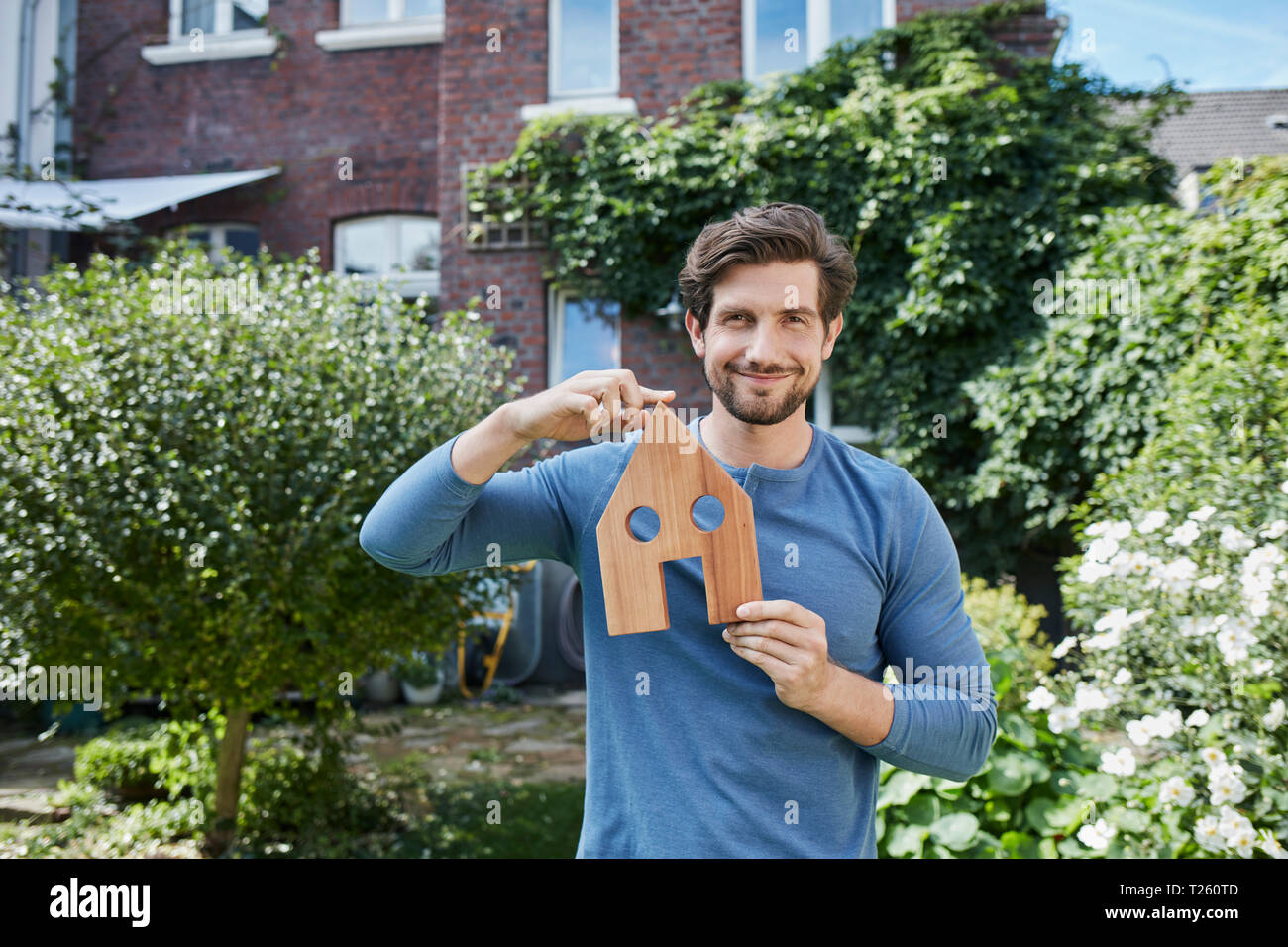 Portrait of smiling man in front of his home holding house model Stock ...