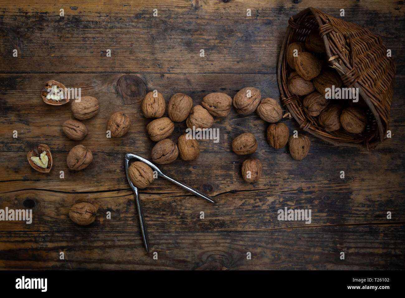Wickerbasket, whole and cracked walnuts and nutcracker on wood Stock ...