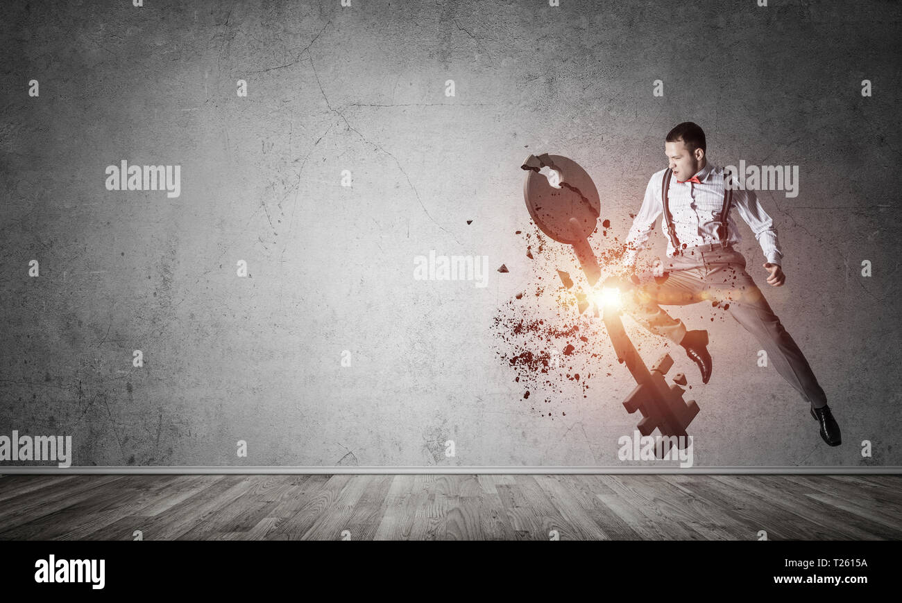 Determined businessman jumping and breaking with kick stone key figure ...