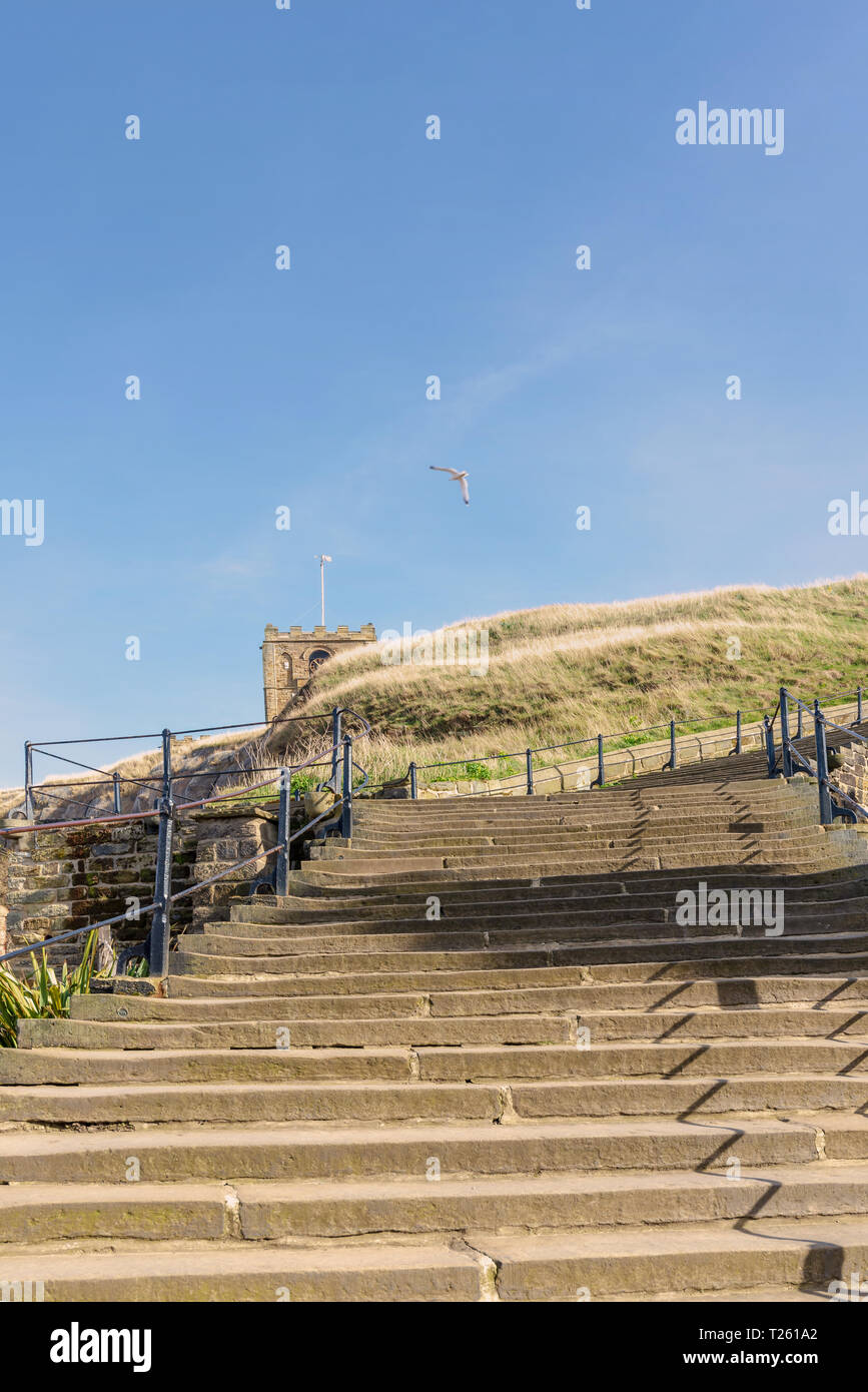 The famous steps leading up to Whitby Abbey. A church tower peers over ...