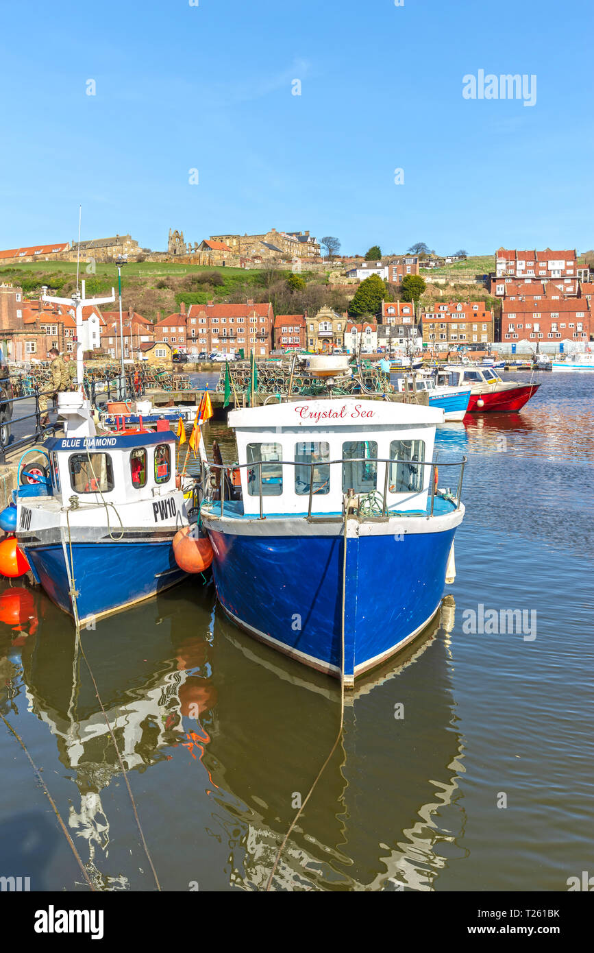 Two small fishing boats in Whitby harbour reflected in the water ...