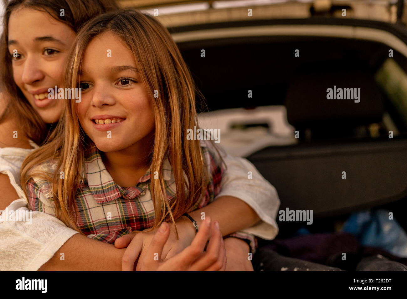 Two happy sisters sitting at opened car boot Stock Photo - Alamy