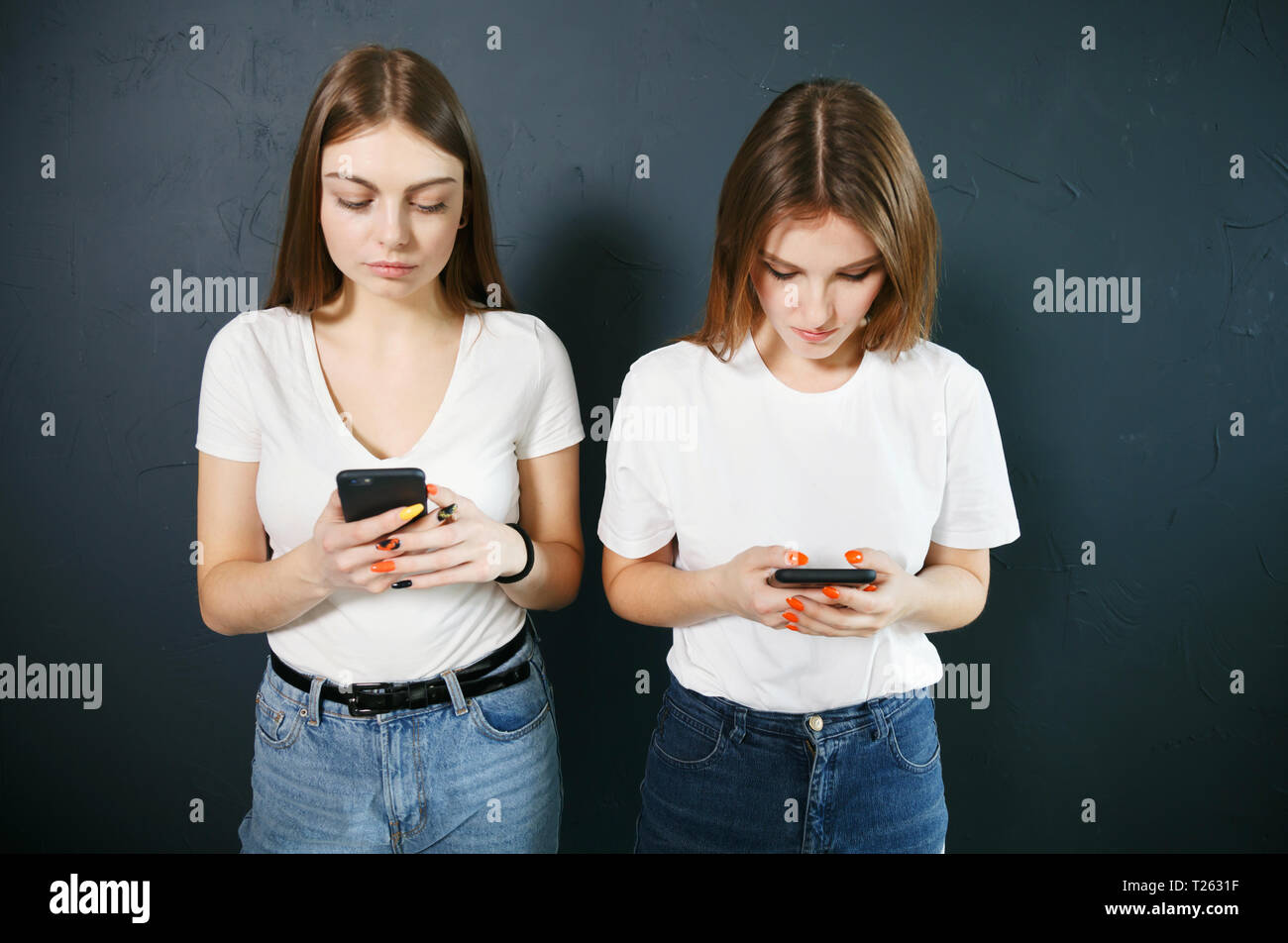 Two internet addicted student girls using smartphones at the gray ...