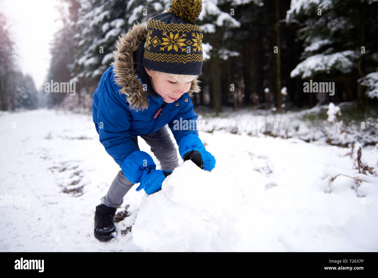 Little boy building snowman Stock Photo - Alamy