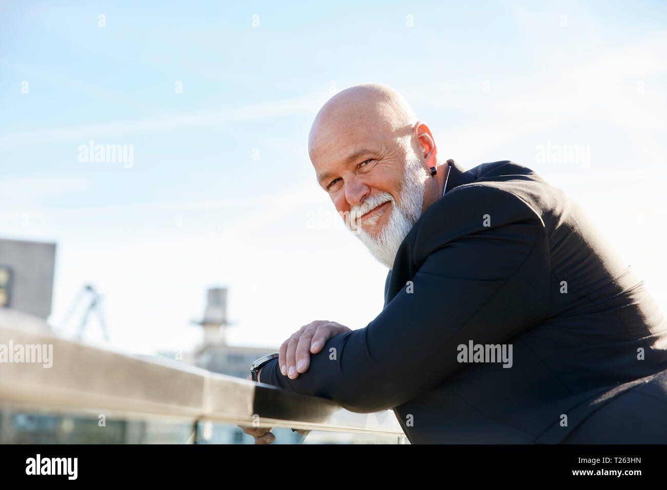 Elegant businessman standing in the city, leaning on railing, enjoying ...