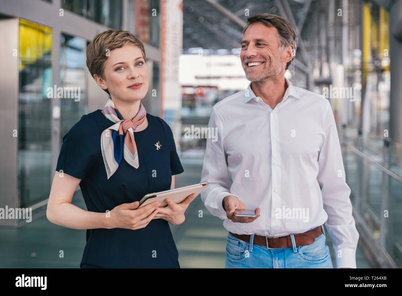 Airline employee with tablet and passenger with cell phone at the ...