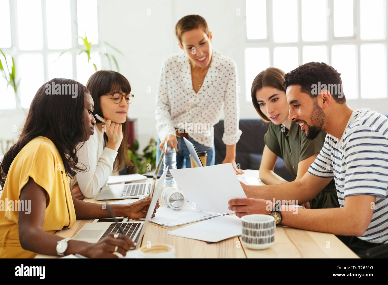 Smiling colleagues working together at desk in office Stock Photo - Alamy