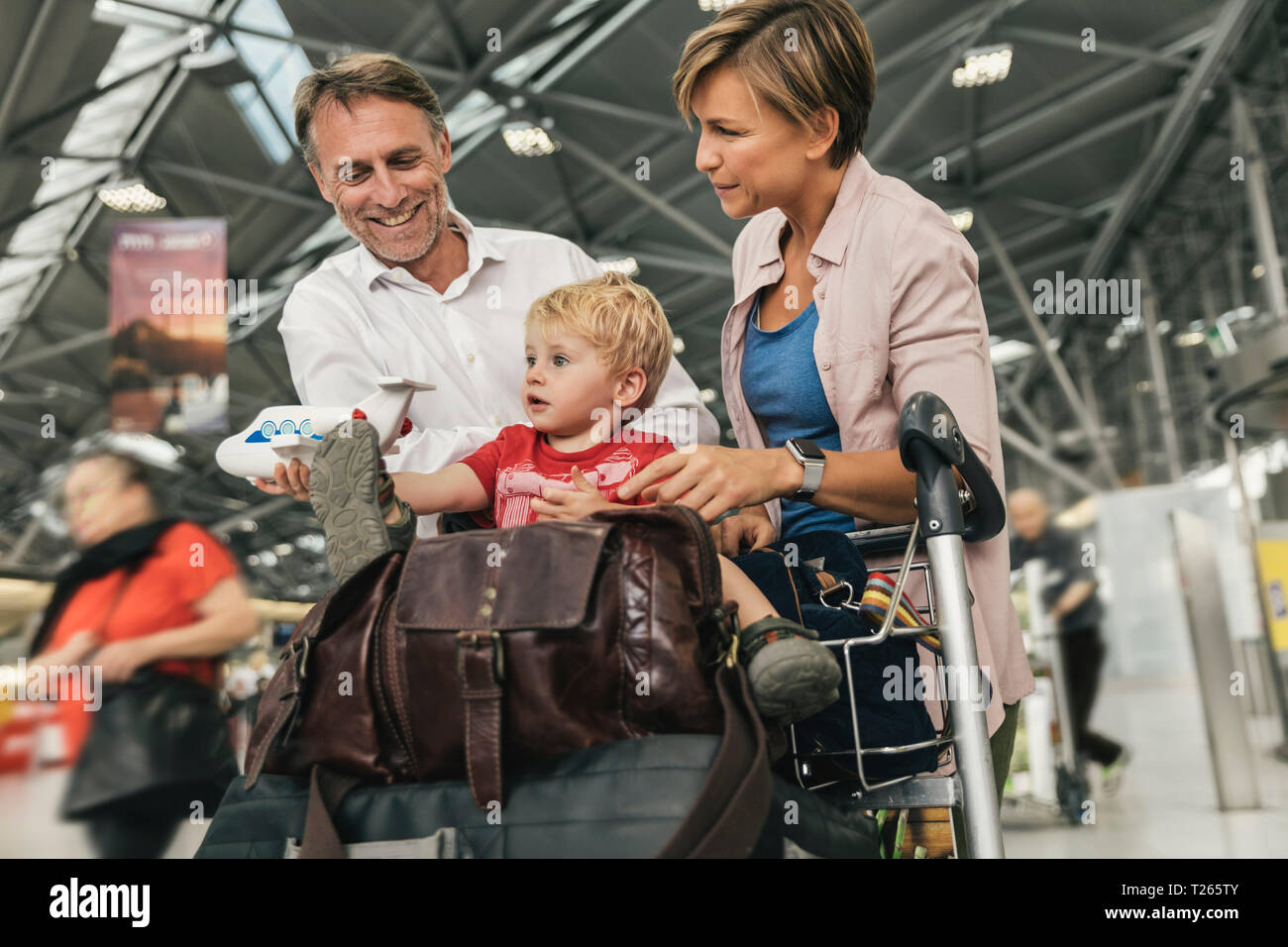 Happy family with baggage cart at the airport Stock Photo - Alamy