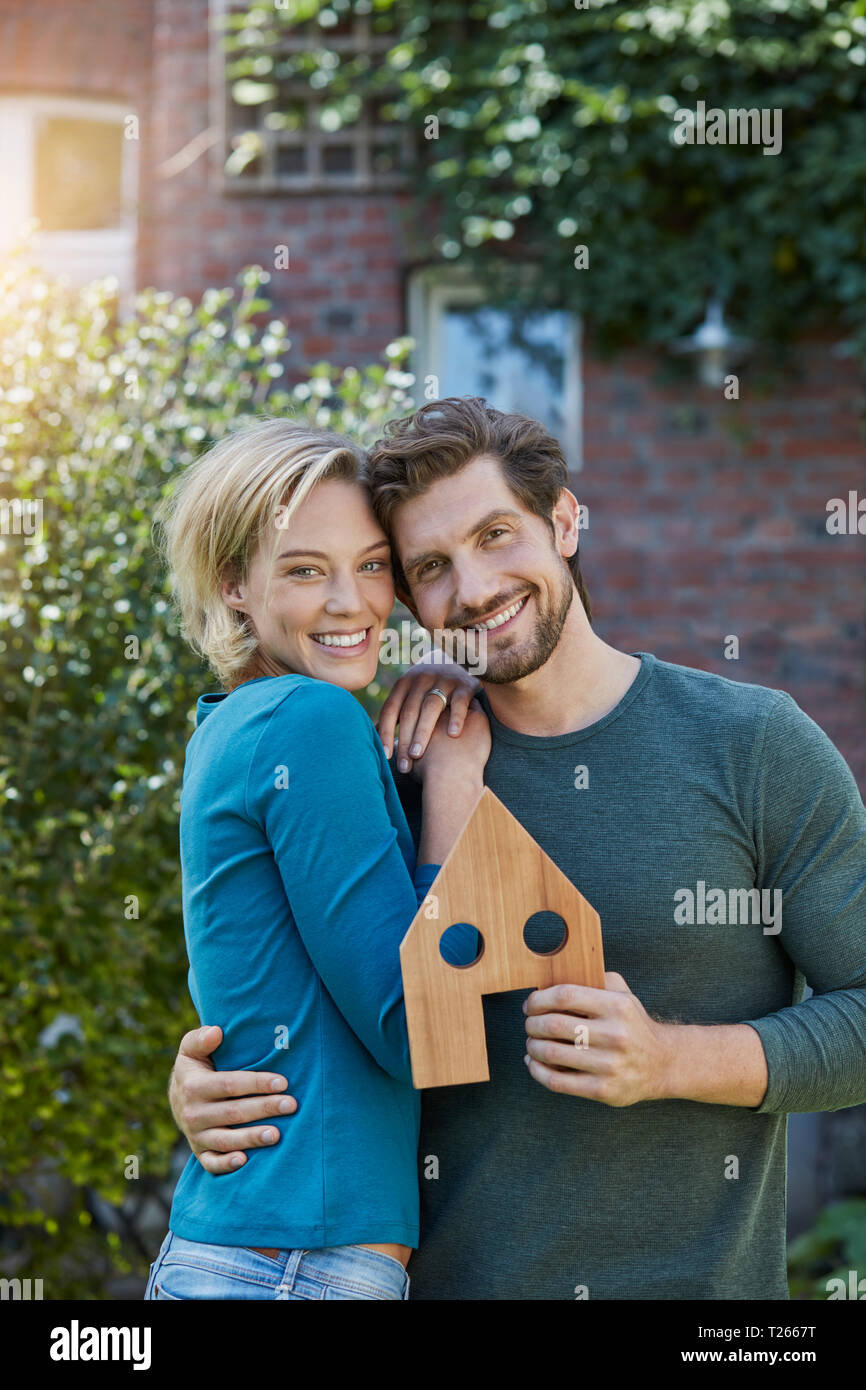 Portrait of happy couple in front of their home with house model Stock ...