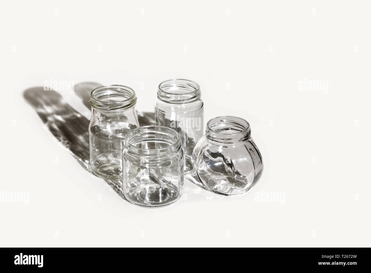 Four clean glass jars on white table with shadow. Set of empty jars ...