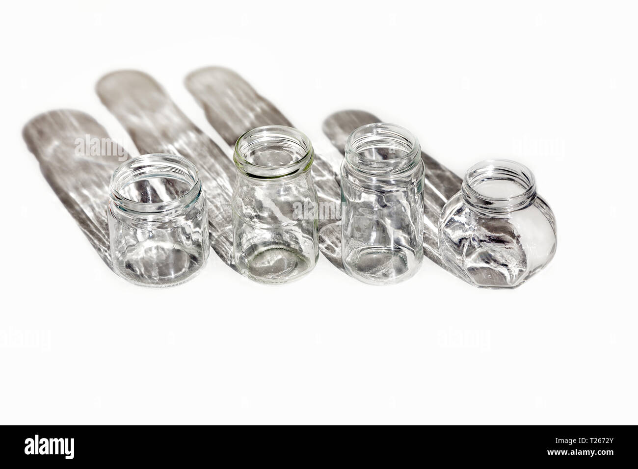 Four clean glass jars on white table with shadow. Set of empty jars ...