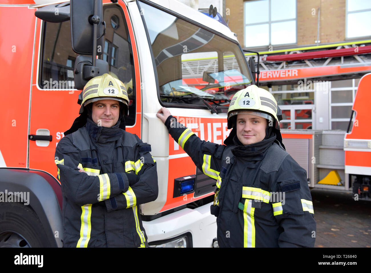 Portrait of two confident firefighters in front of fire engine Stock ...