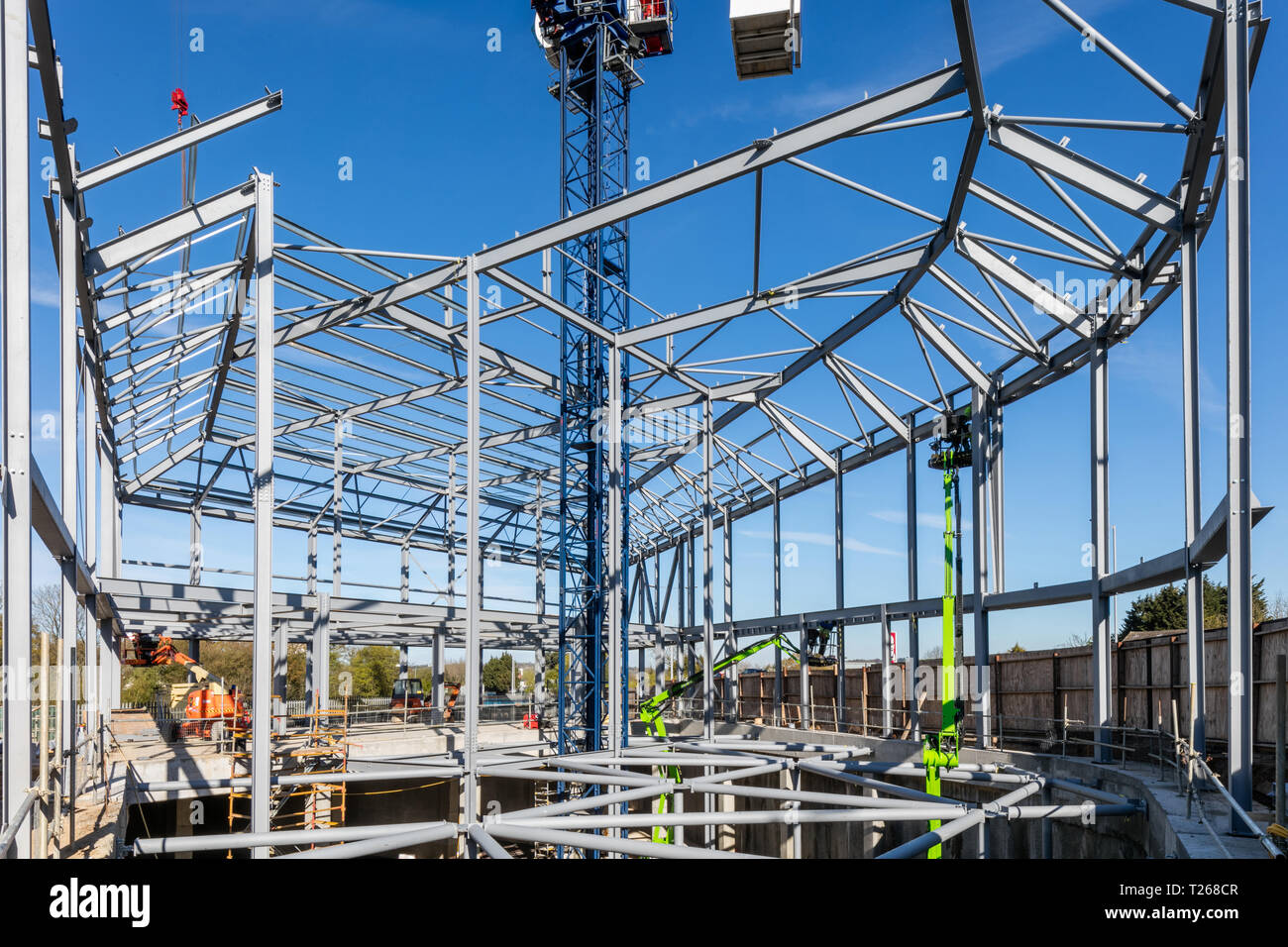 Steel frame of new building in construction set against bright blue sky ...
