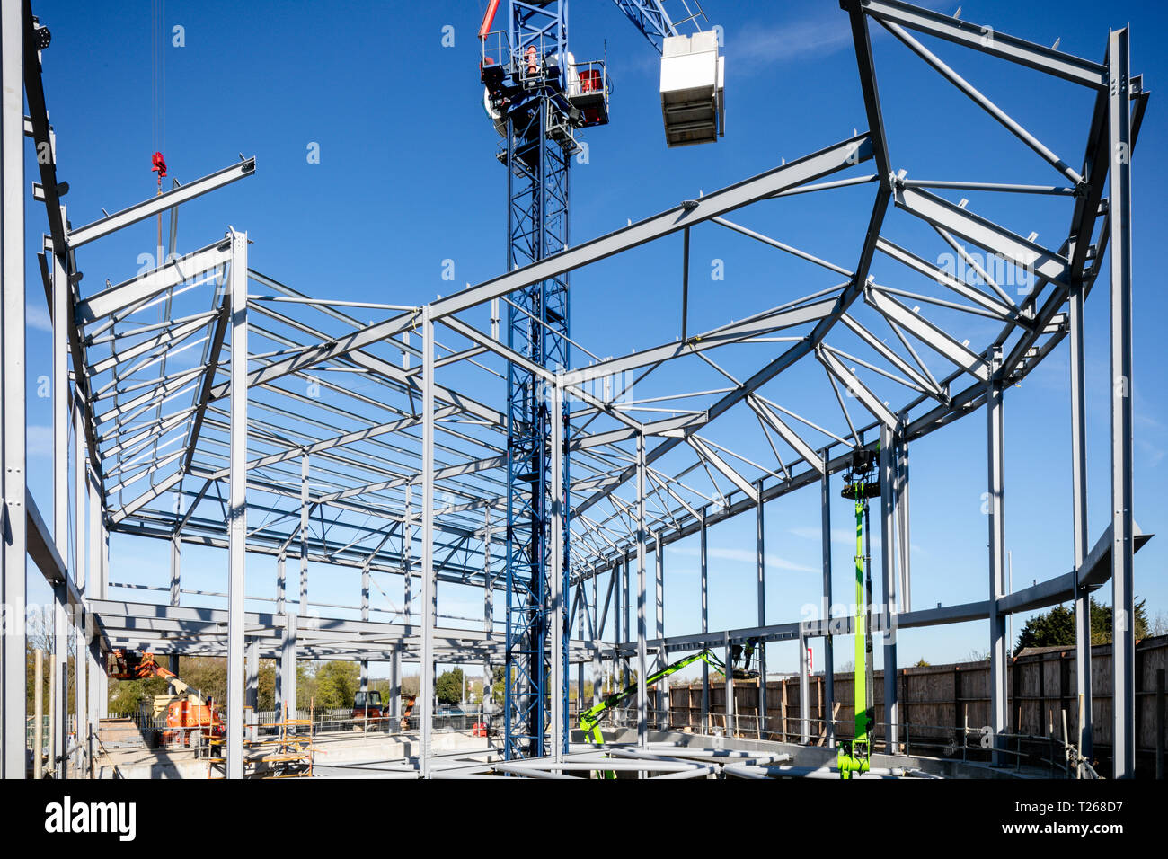 Steel frame of new building in construction set against bright blue sky ...