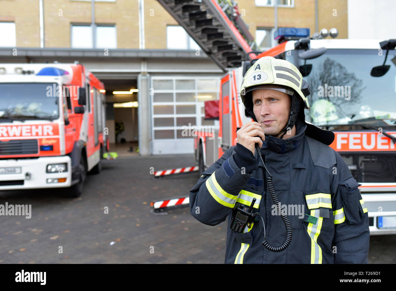 Firefighter standing on yard at fire engine using walkie talkie Stock ...