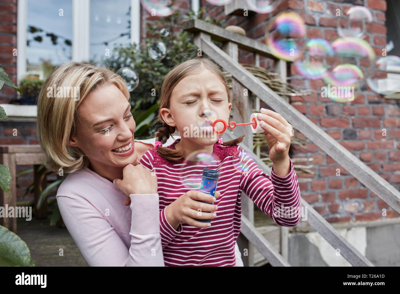 Happy mother and daughter making soap bubbles Stock Photo - Alamy