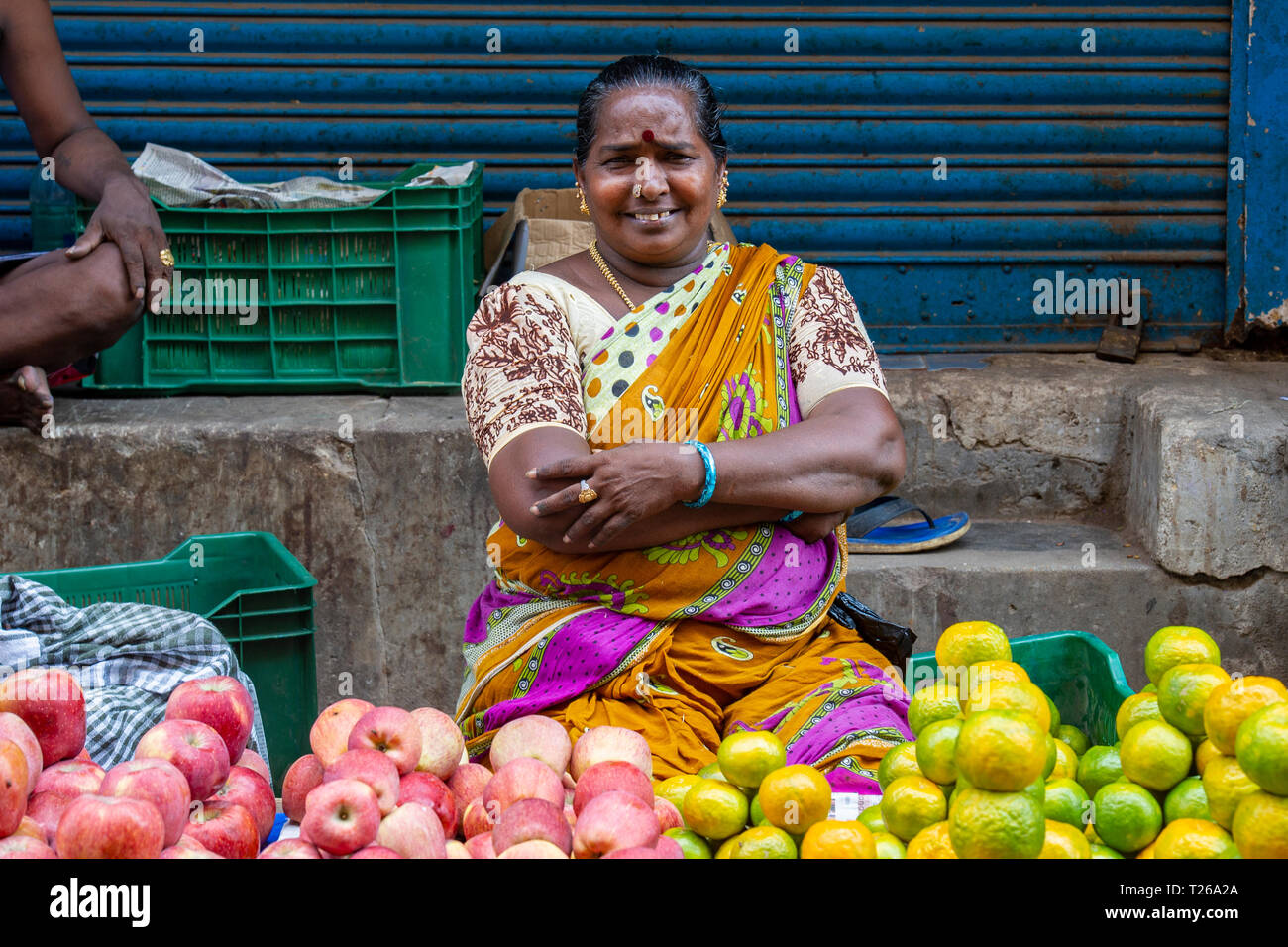 A smiling lady in the street market selling various fruits Stock Photo ...
