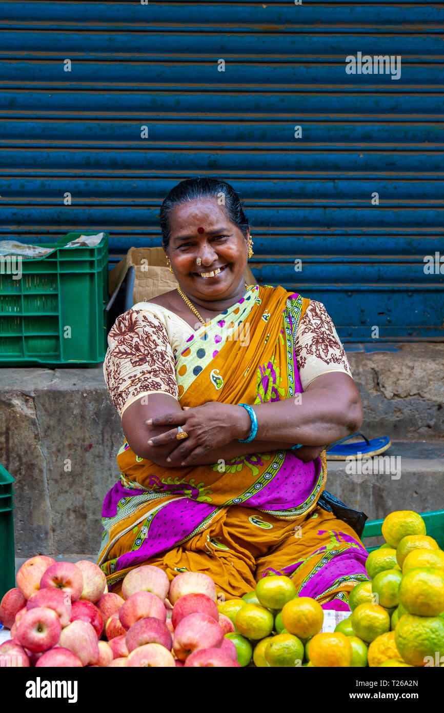 A smiling lady in the street market selling various fruits Stock Photo ...