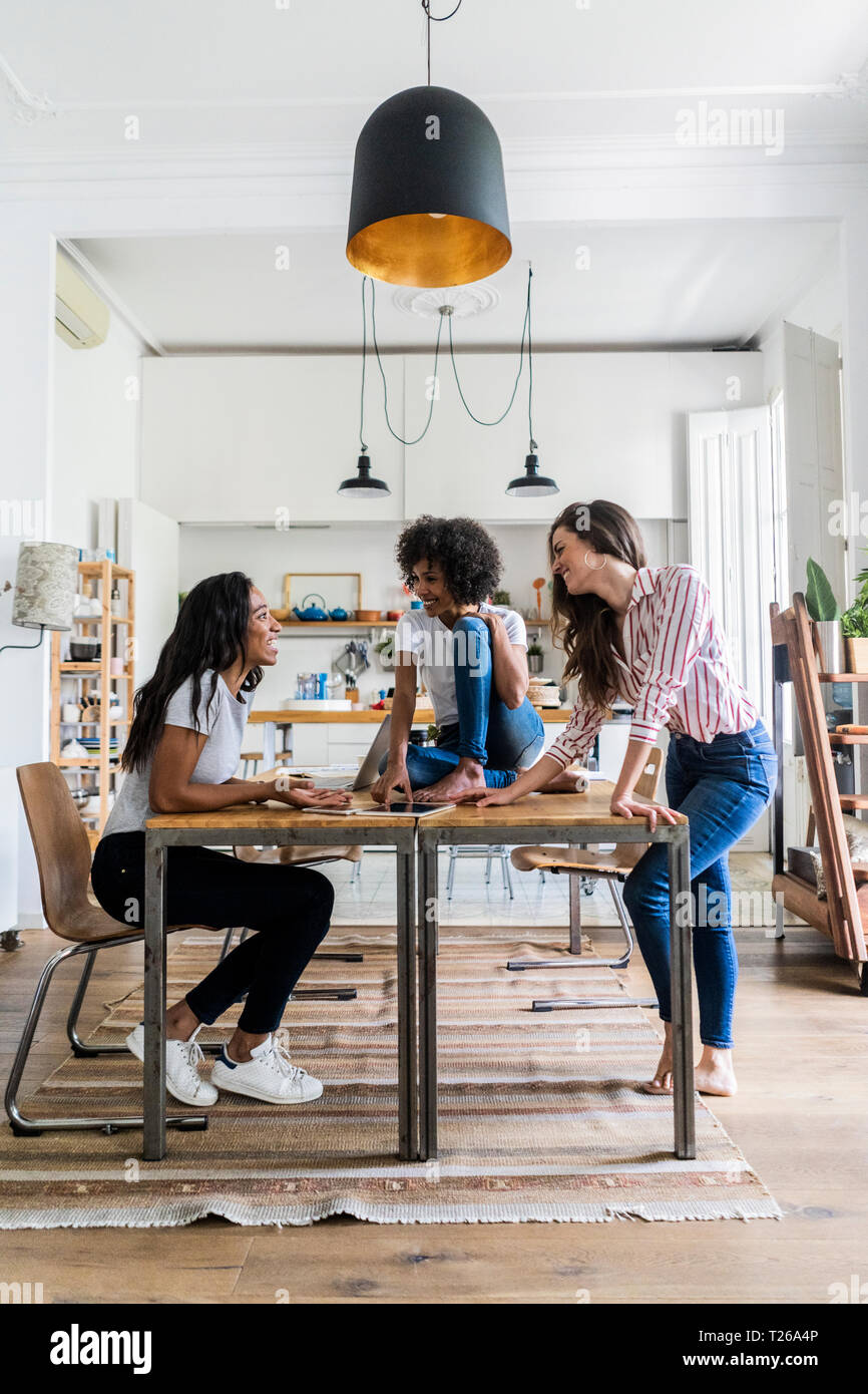 Three happy women talking at table at home Stock Photo - Alamy