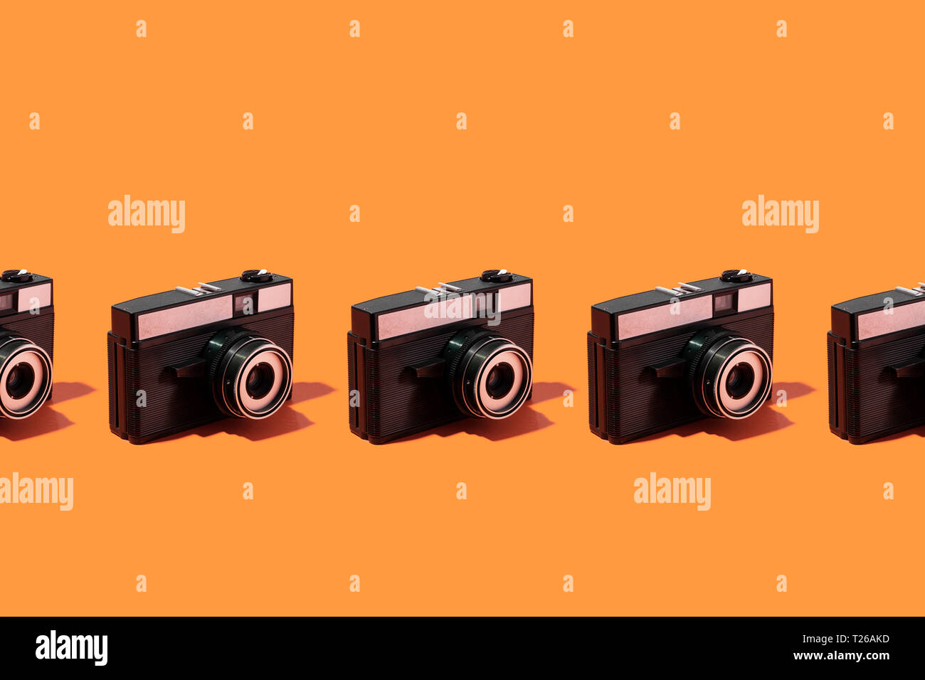 Plastic photo cameras organized in a row over orange background Stock ...