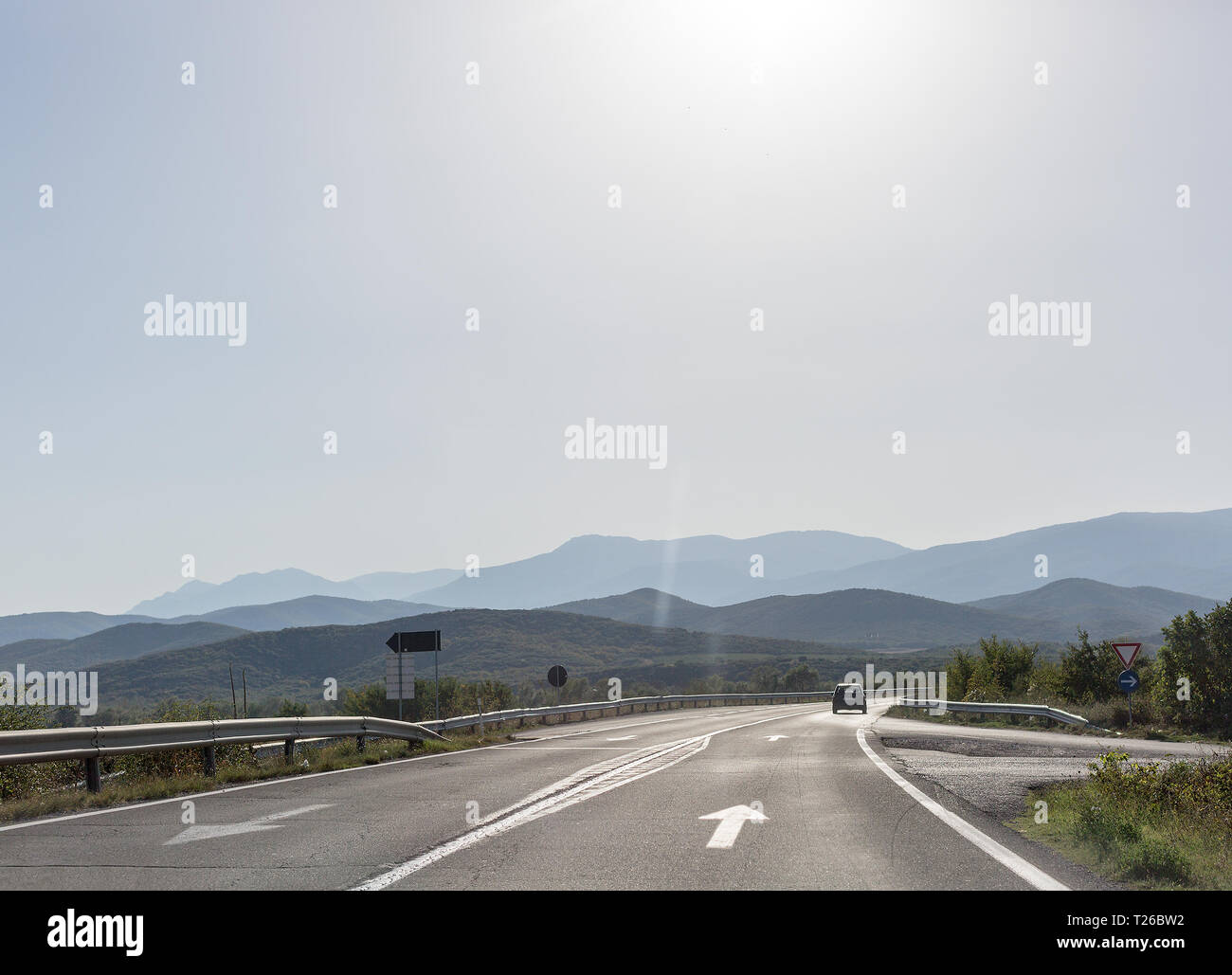 Asphalt road with a lonely car on the background of mountains. Space ...
