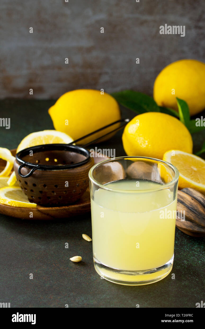 Cold drink with freshly squeezed lemon juice and fresh lemons on a dark ...