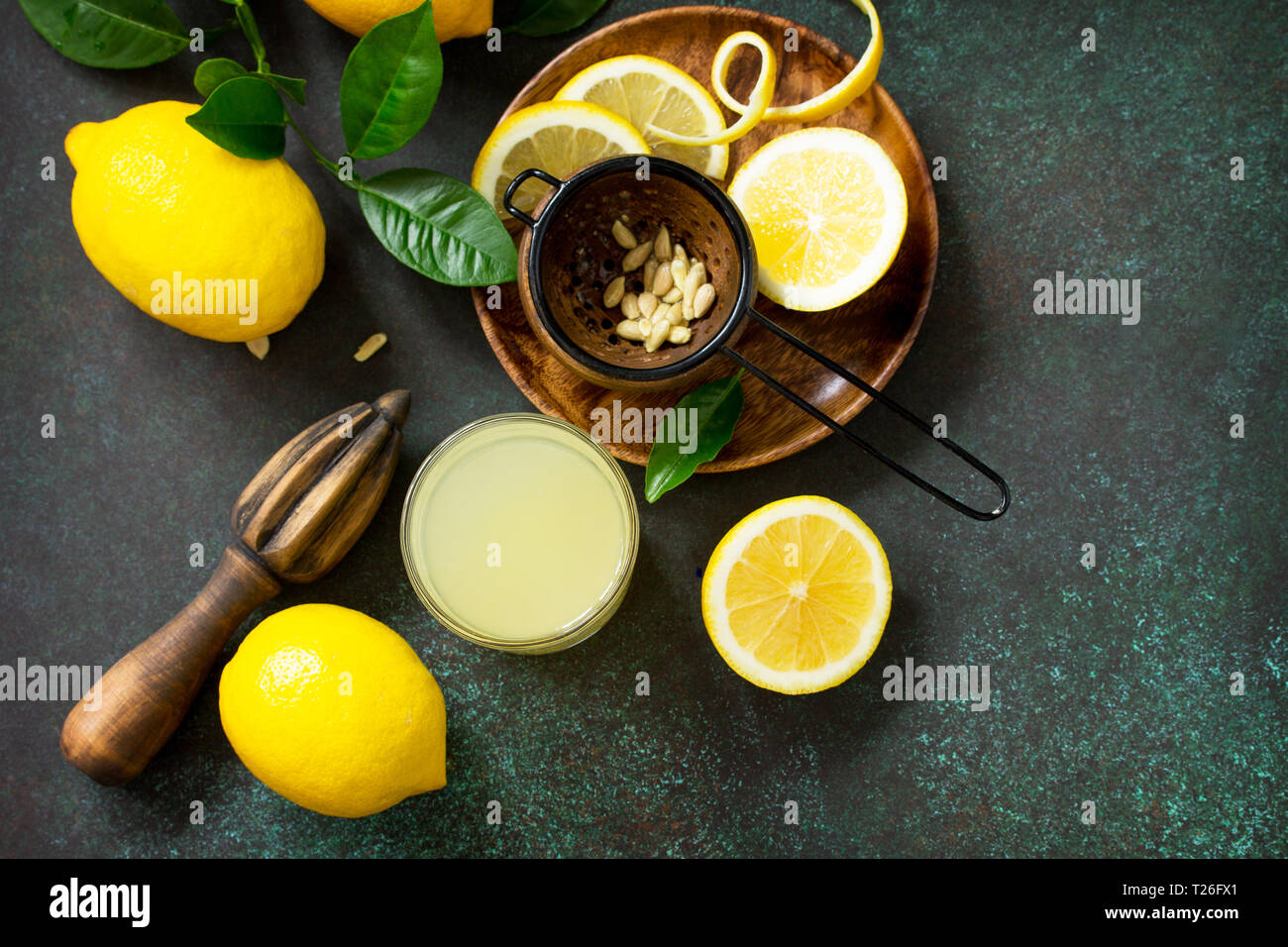 Cold drink with freshly squeezed lemon juice and fresh lemons on a dark ...