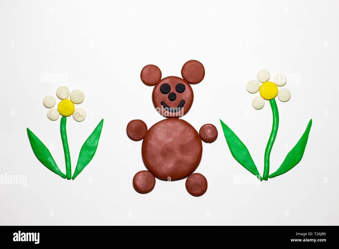 Brown bear among the flowers are made of plasticine. The bear is a ...