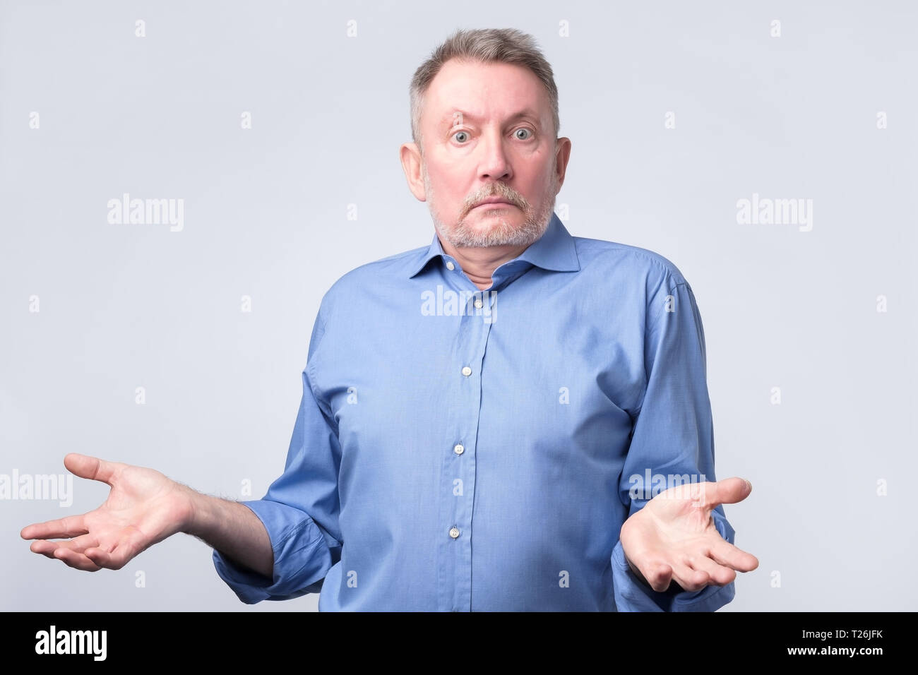 Confused senior caucasian man in blue shirt is unsure in studio. Studio ...