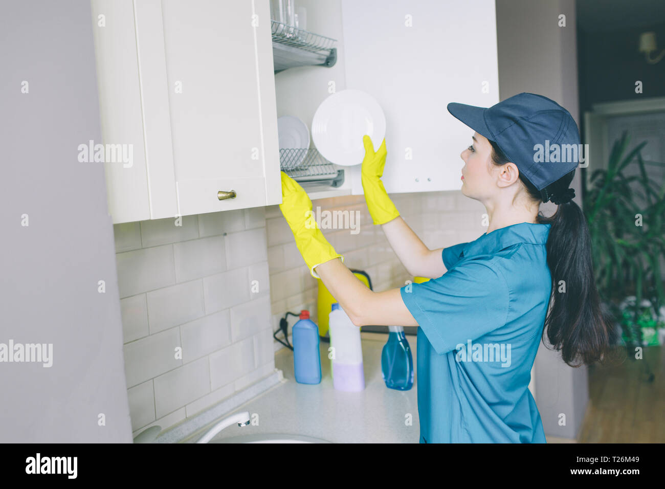 A picture of cleaner putting plate in cupboard. It is opened. Girl ...