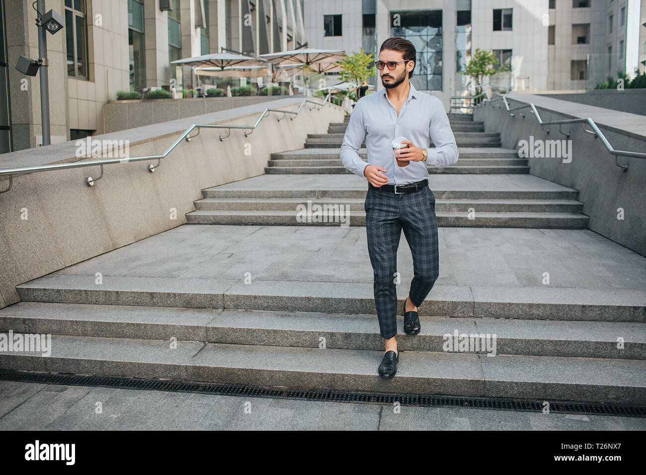 Picture of attractive young man walks on steps and looks to left. He ...