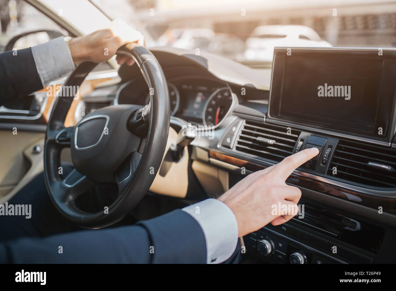Cut view of man sitting in luxury car. He holds one hand on steering ...