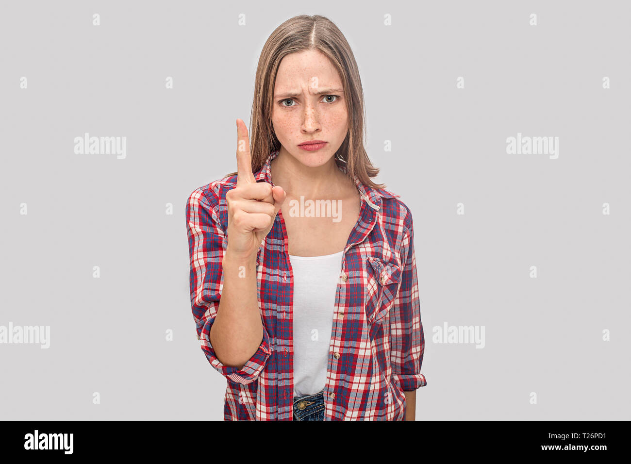 Sad and unhappy young woman points up. She looks on camera with sad ...