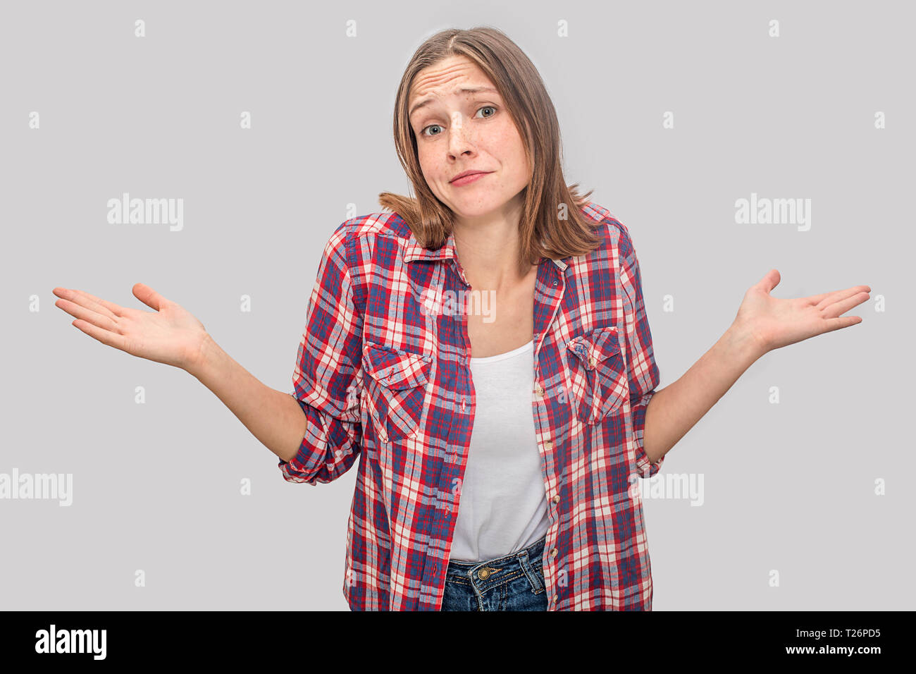 Young woman with neutral mood stands and looks on camera. She holds ...