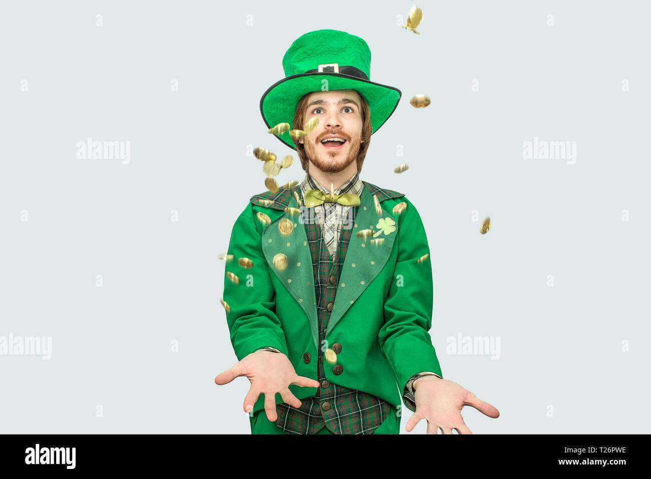 Happy rich young man in saint Patrick's suit spreading golden coins up ...